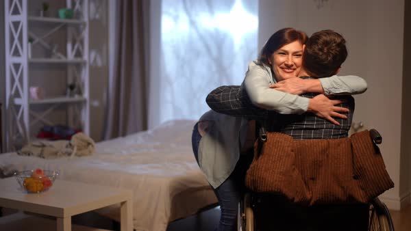 Loving smiling wife hugging husband in wheelchair caressing back of ...