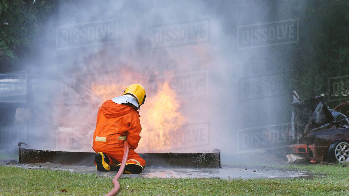 Firefighter fighting with flame using fire hose chemical water foam ...
