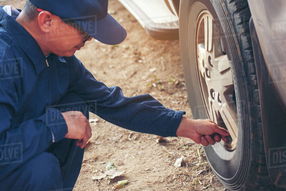 Mechanic man hands checking car tires outdoor on site service auto ...