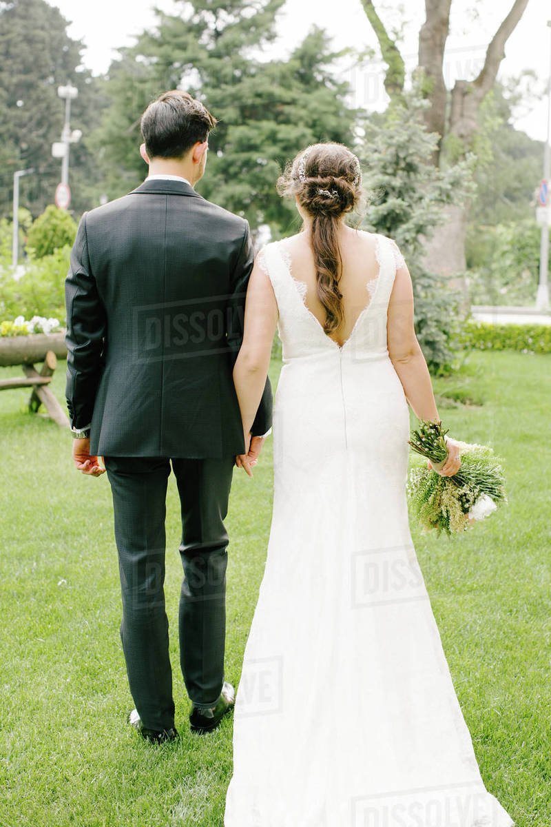 Bride poses groom. They walk with a back-to-back next to a historic ...