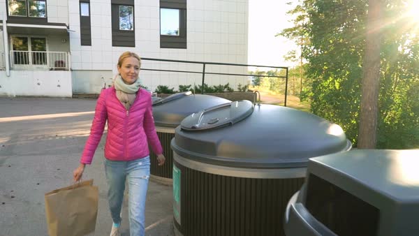 A young woman puting different types of garbage in different recycling ...