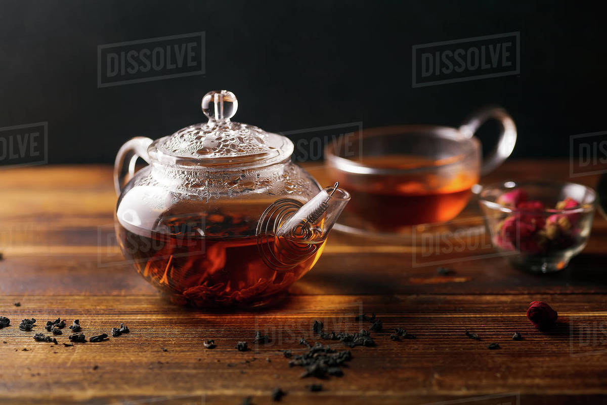 Picture of glass teapot with cup of black tea and golden tray on wooden ...