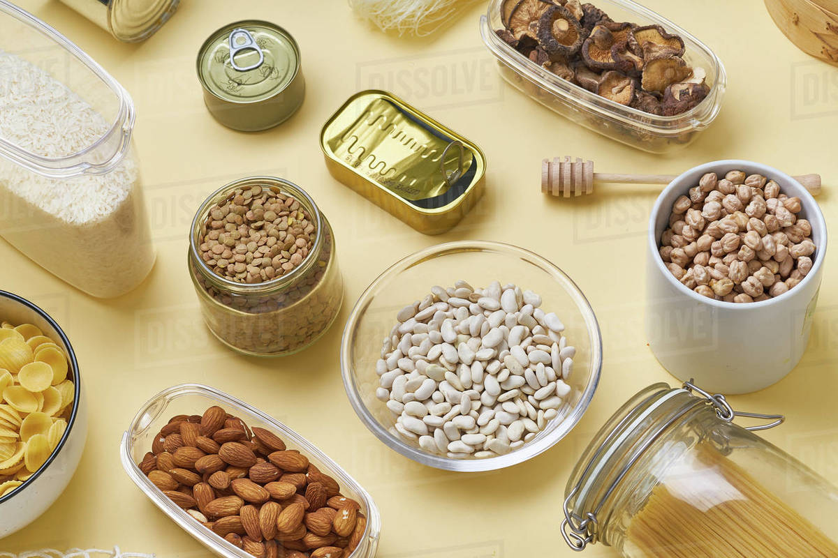 Creative flatlay with pantry staples. Glass jars with pasta, beans and ...