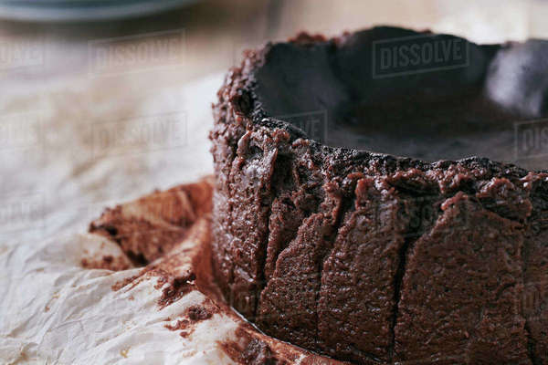Close up of a chocolate basque burnt cheesecake on a wooden table ...
