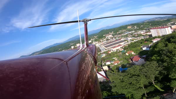 A small red helicopter flies over the city. The footage was taken from ...