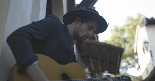 A smiling young man singing and playing a guitar outdoors, Fairhope ...