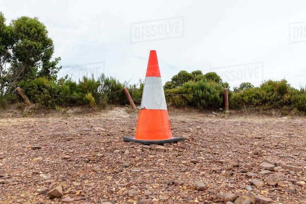 Photograph of an old and damaged orange safety cone with torn ...