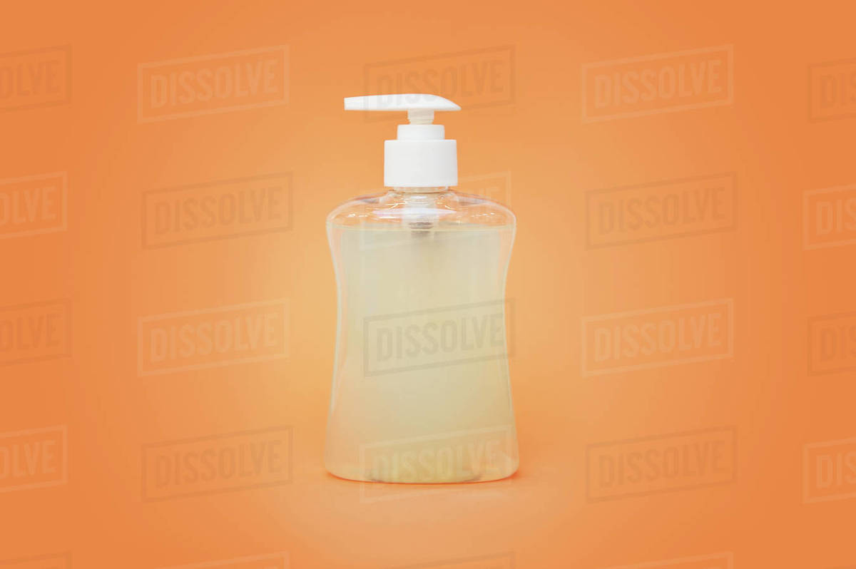Cosmetic bottles of cream, soaps, foams, or shampoo on orange ...