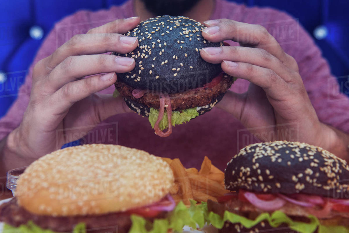 Man eating burgers at table, closeup photo - Royalty-free Stock Photo ...