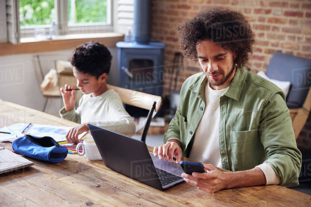 Father using laptop with son doing homework - Royalty-free Stock Photo ...