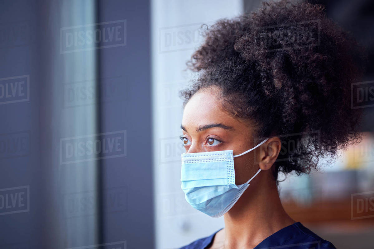 Female Doctor In Face Mask Wearing Scrubs Under Pressure In Busy ...