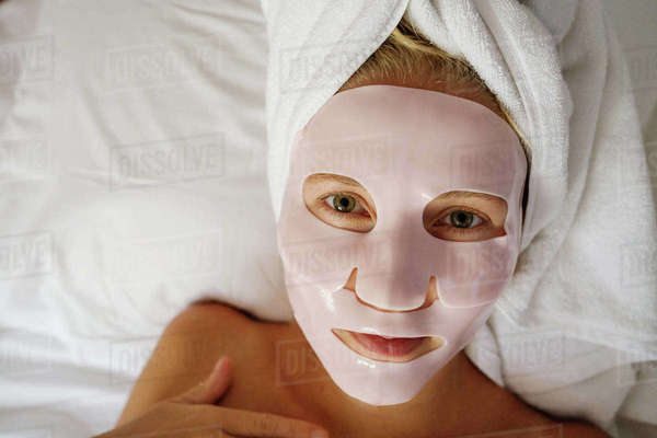 Woman laying in bed wearing a face mask. - Stock Photo - Dissolve