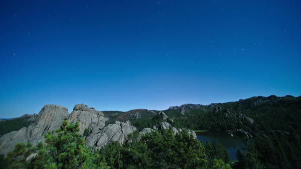 Timelapse footage of stars crossing a night sky lit blue by the Moon ...
