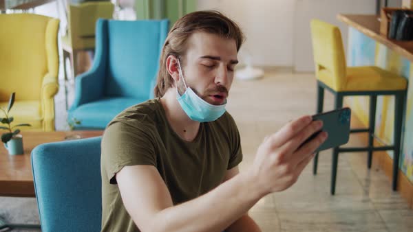 man in medical mask during video conference call on the phone, video ...