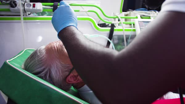 Close-up of unconscious old male patient lying on stretchers with ...