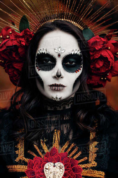 Portrait of young woman with sugar skull makeup and red roses dressed ...