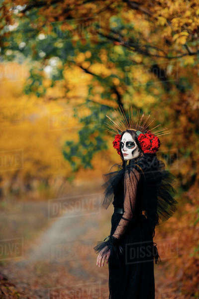 Young woman with sugar skull makeup and red roses dressed in black ...