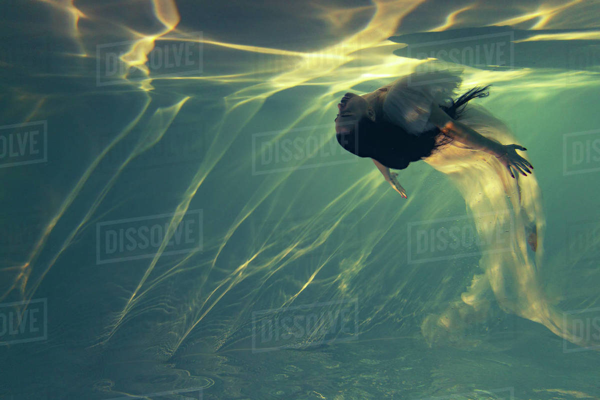 Underwater shoot of beautiful woman in white flying transparent dress ...