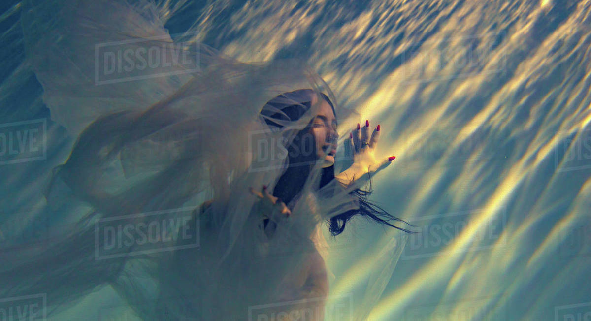 Underwater shoot of beautiful woman in white flying transparent dress ...