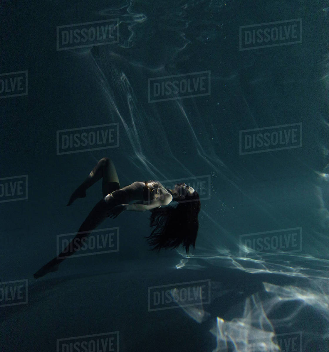 Underwater shoot of beautiful woman with long hair dancing in water in ...