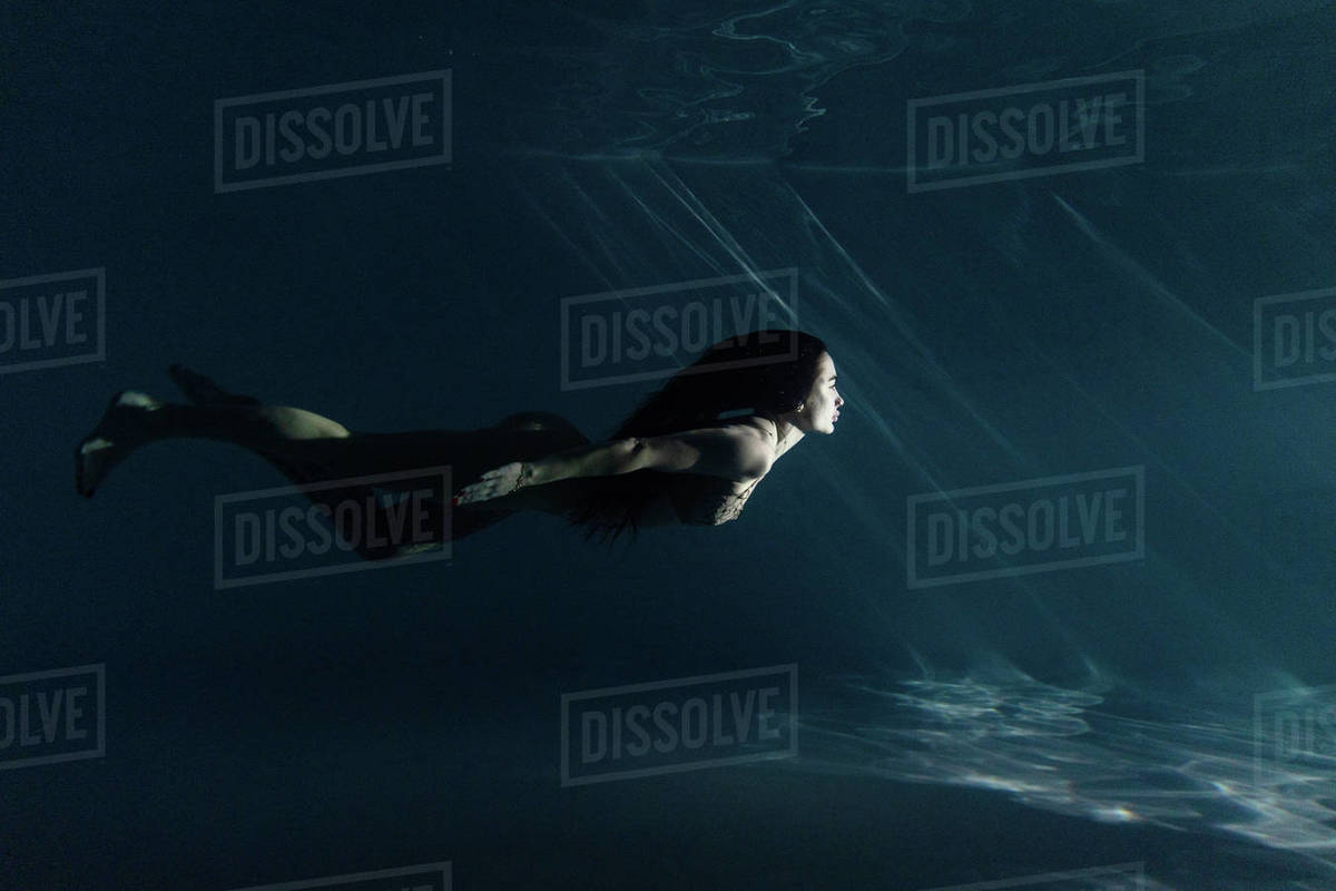 Underwater shoot of beautiful woman with long hair swimming in water in ...