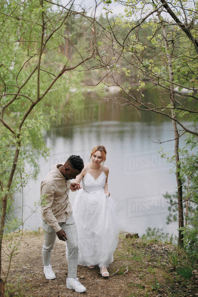 Happy interracial couple newlyweds holds each other hands and walks ...