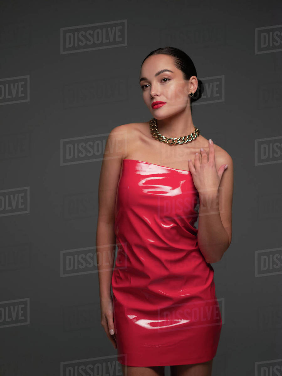 Young pretty brunette woman poses in stylish red latex dress and chain ...