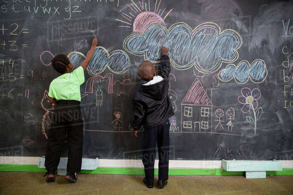 Two school kids drawing on the blackboard in classroom - Royalty-free ...