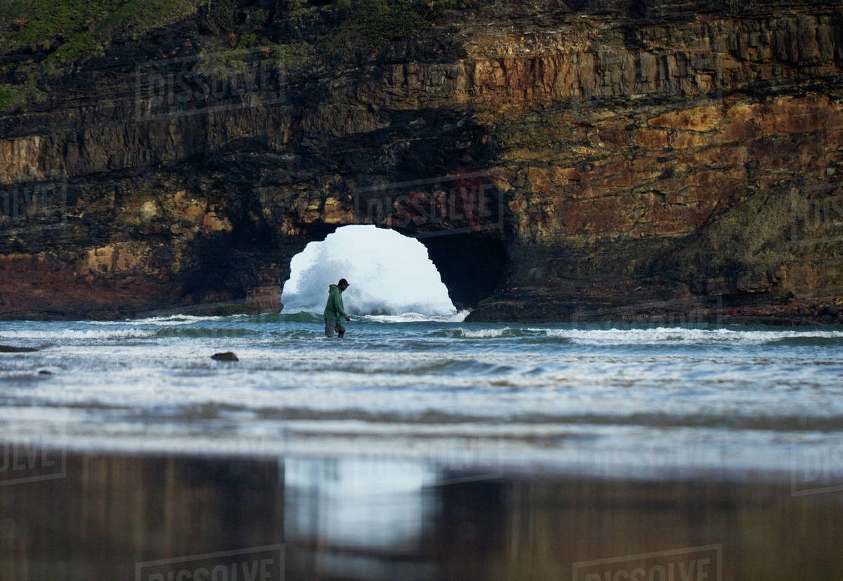 Man wading through water at Hole in the Wall - Stock Photo - Dissolve