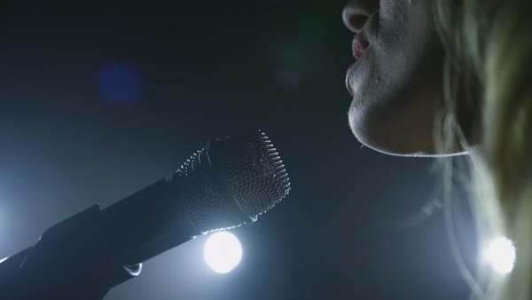 Close-up of the face of the singer with microphone on a black smoky ...