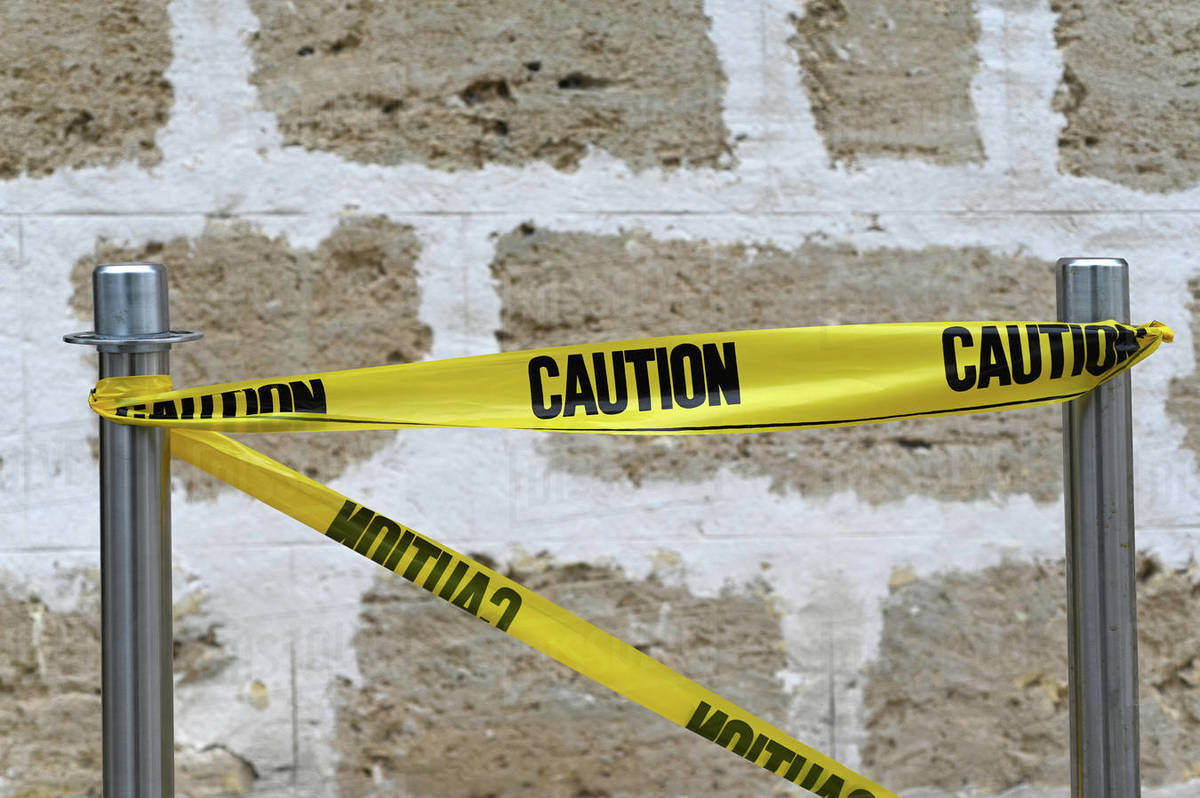Caution tape on a metals poles in front of a brick wall. - Royalty-free ...