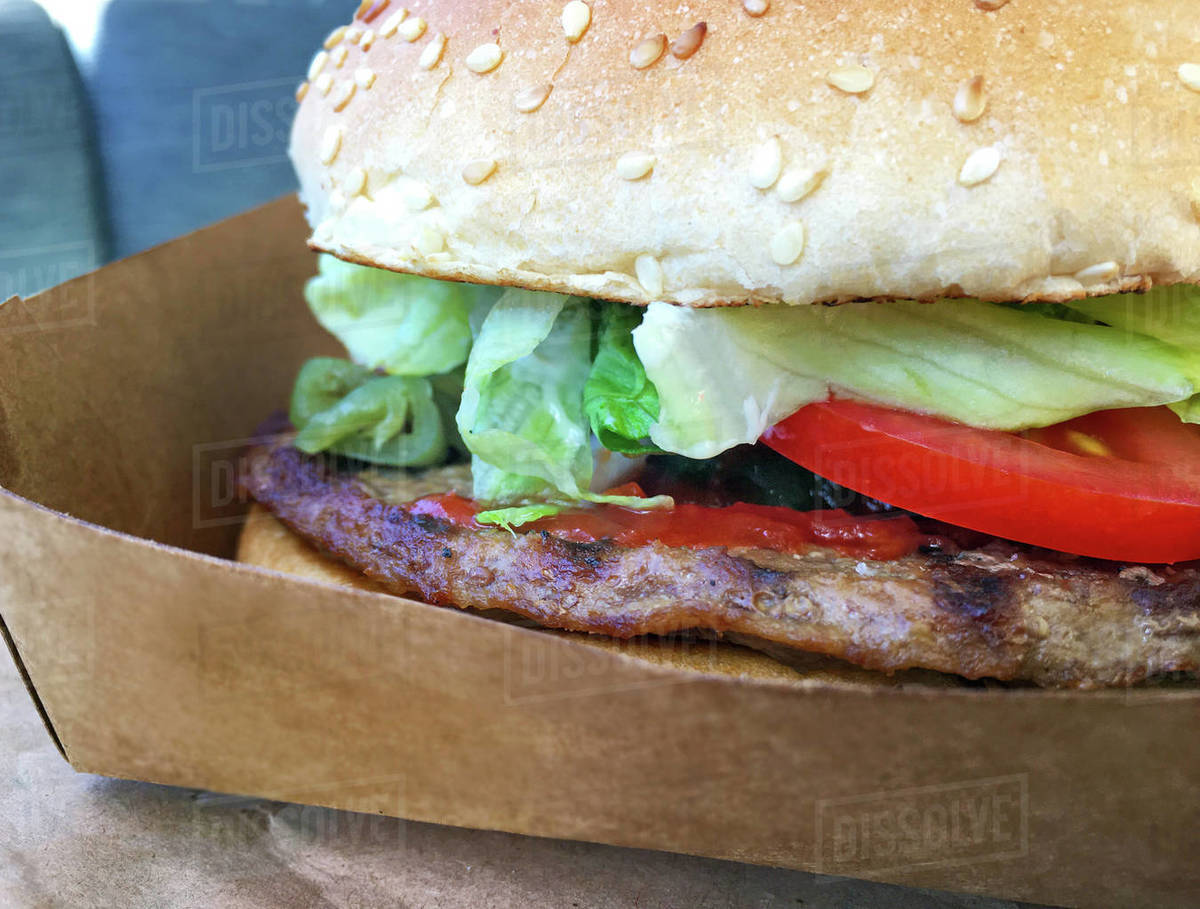 Close up of meat patty inside a hamburger bun with letters and slice of ...