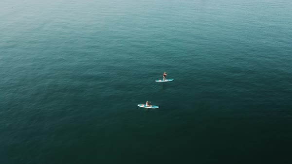 People paddling on paddle boards within clear blue sea - Stock Video ...