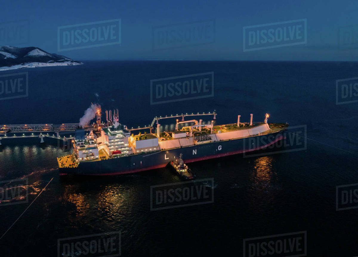 A large LNG tanker docks at an industrial port terminal for cargo ...