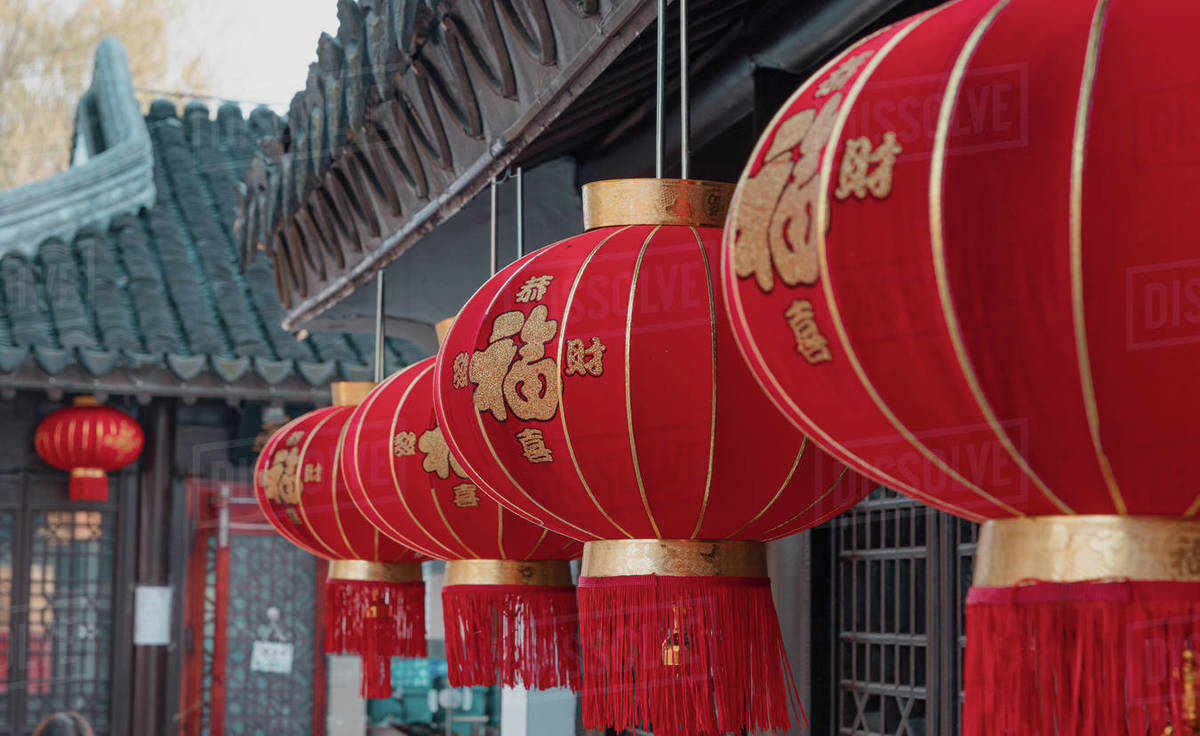A series of bright red lanterns adorned with golden characters ...