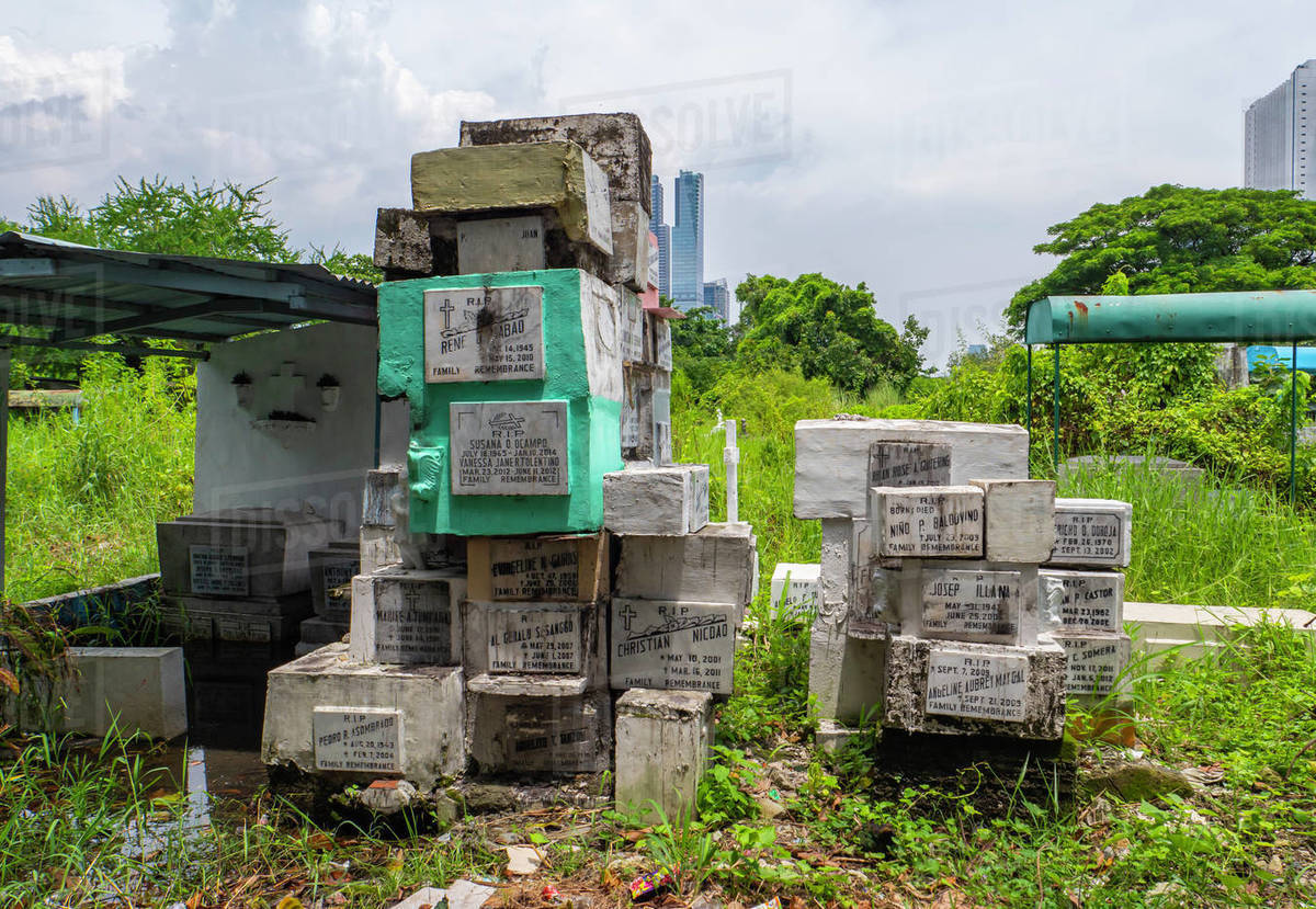 Tall burial structures stand in a cemetery, surrounded by green foliage ...