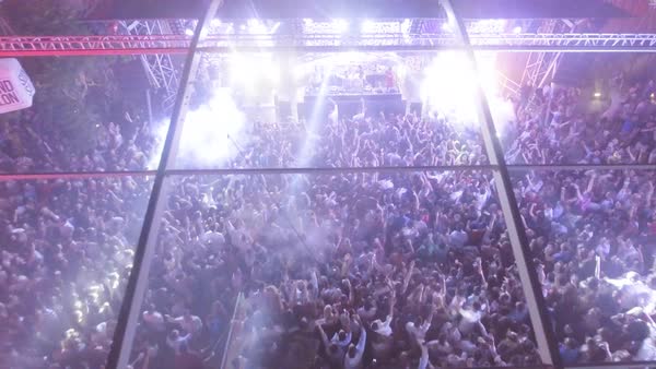 Aerial over a massive indoor outdoor rock concert or dance club at ...
