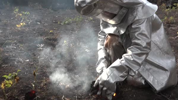 A man in a fireproof suit examines lava flows from the Cabo Verde ...