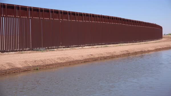 A tributary of the Colorado River flows along the border wall between ...