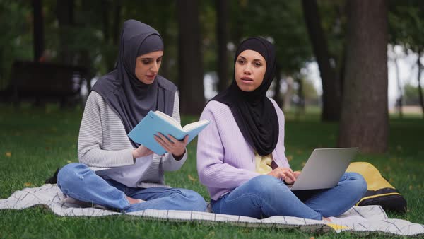 Muslim female students in hijabs getting ready for exam together, using ...