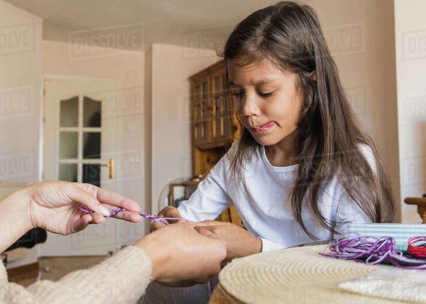 Hispanic cute girl concentrated making hand made thread bracelets at ...