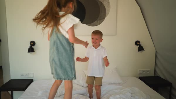 Children play actively on bed at glamping. Smiling little boy catches ...