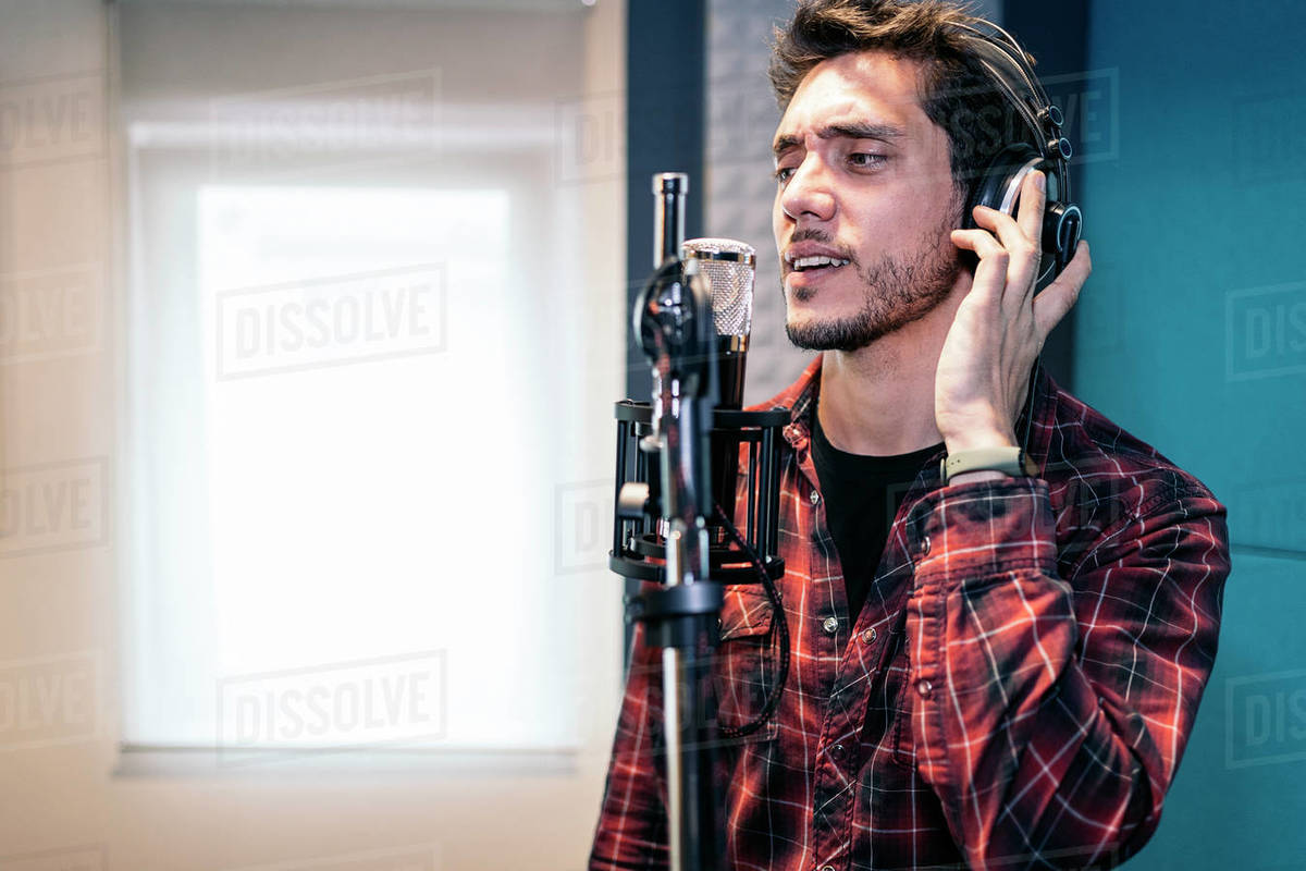 Young musician singing into microphone while working on songs during a ...