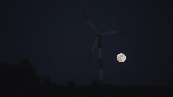 Wind turbine rotating against the full moon background at night ...