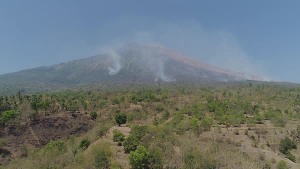 slopes volcano with forest fire, farmland at foot of the volcano Agung ...