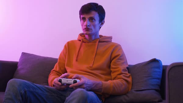 Young gamer man playing video game on TV with modern console in neon ...