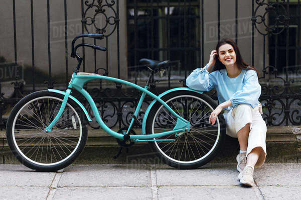 Adorable young lady with dark hair relaxing outdoors near retro blue ...