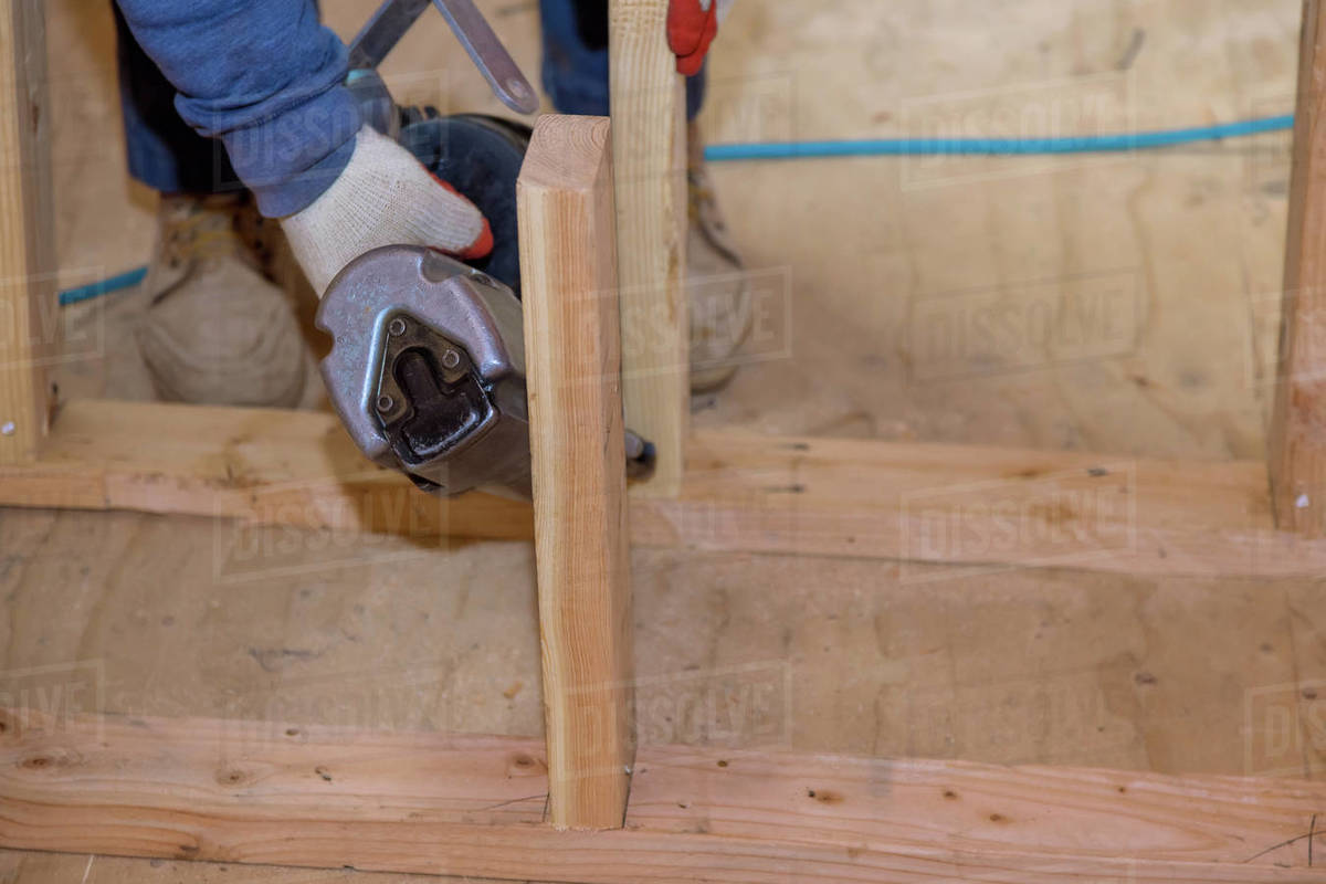 A carpenter for nailing wooden beam using an air hammer on construction ...