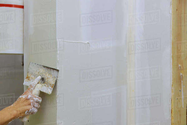 Builder puts plaster on the wall hand holding a spatula with ...