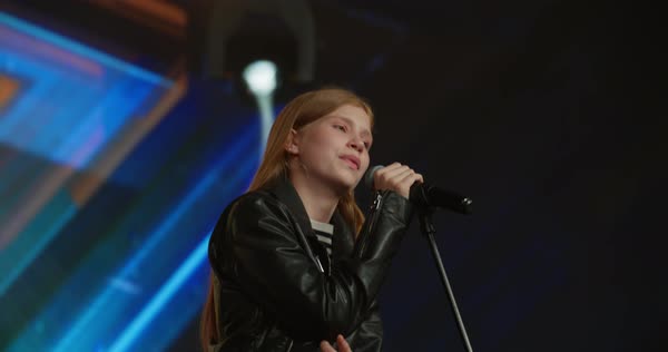 Young teenager girl singer performing on stage, contestant singing ...